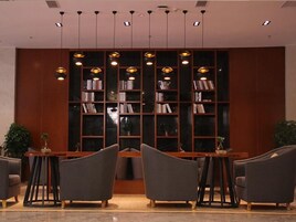 Um hall com área de estar central, estante de livros e iluminação pendente.
