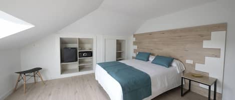 Quarto com teto inclinado, cama com cabeceira de madeira, mesa de cabeceira e prateleiras embutidas.