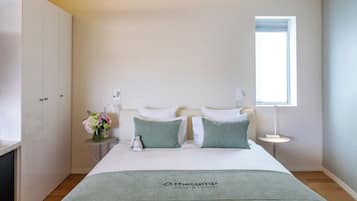 Quarto de hotel com cama, mesa de cabeceira, janela e guarda-roupa.