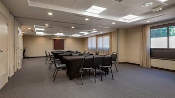 Uma sala de conferências com uma mesa comprida, cadeiras e uma tela de projeção.