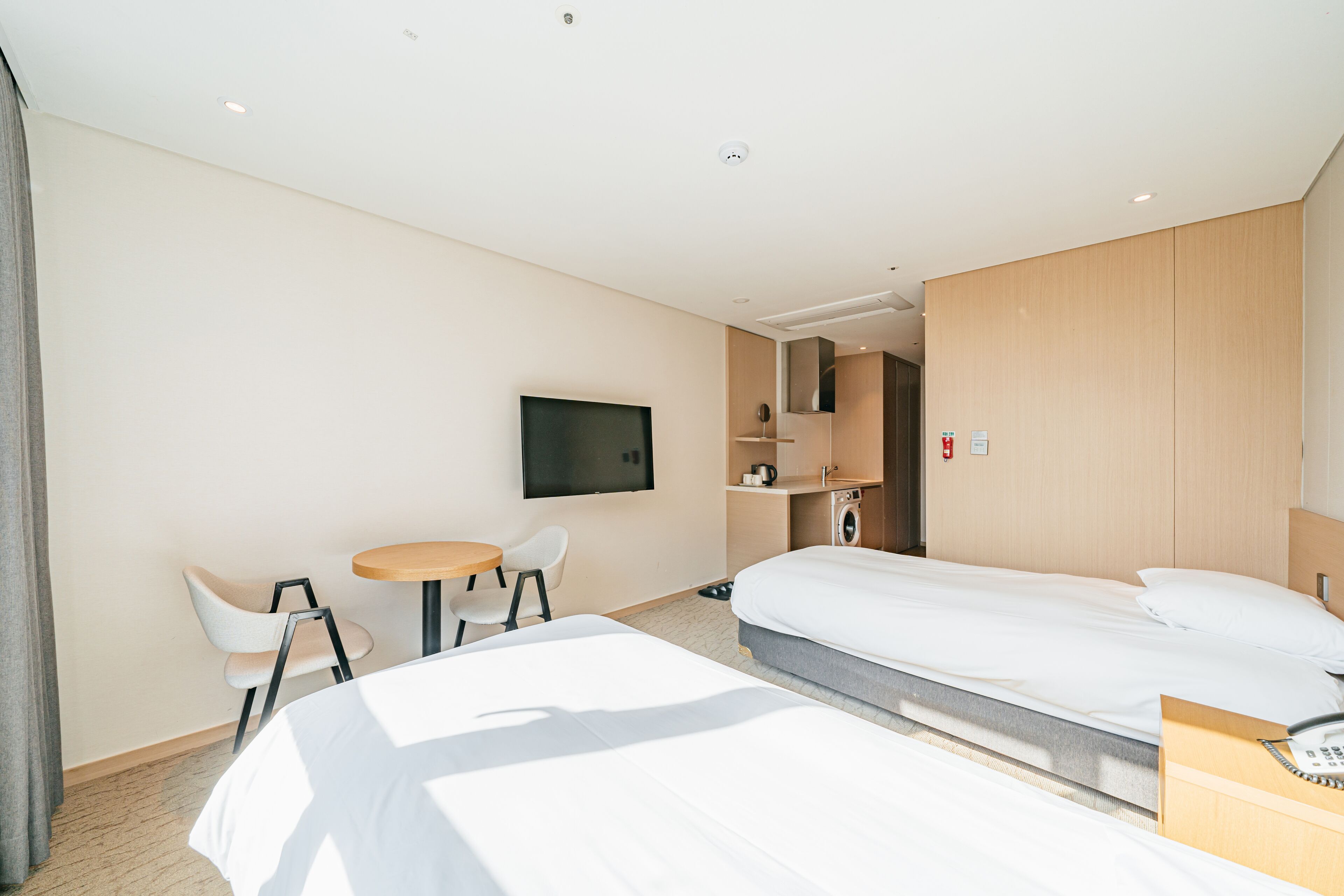 Quarto de hotel com duas camas, televisão, uma mesinha e uma cadeira.