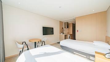 Quarto de hotel com duas camas, televisão, uma mesinha e uma cadeira.