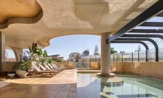 Uma área de piscina externa com espreguiçadeiras e plantas em vasos.