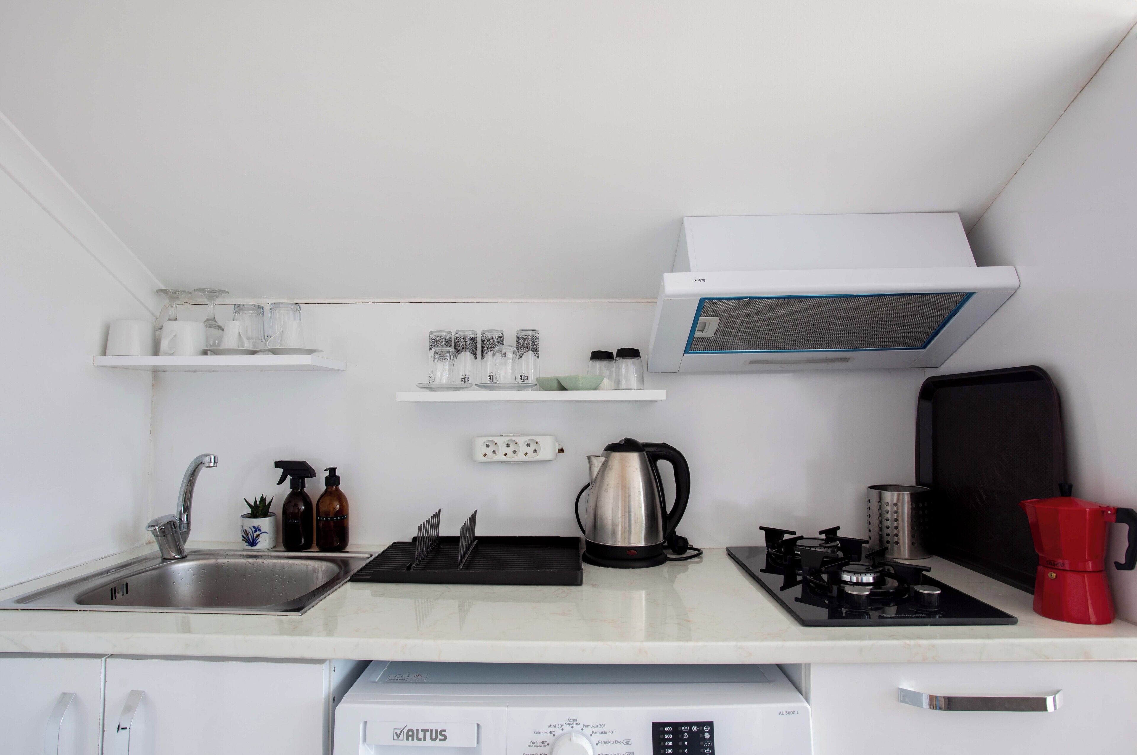 Cozinha compacta com pia, fogão e diversos eletrodomésticos.