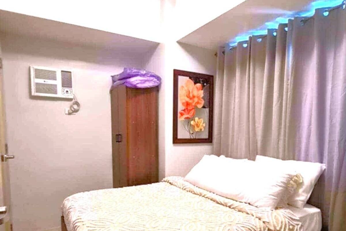 Quarto com cama, porta, ar-condicionado fixado na parede e um quadro.