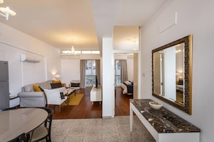 Uma sala de estar moderna com área de jantar, um espelho grande e vista para a varanda.