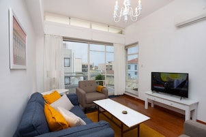 Uma sala de estar moderna com sofá, poltrona e televisão.