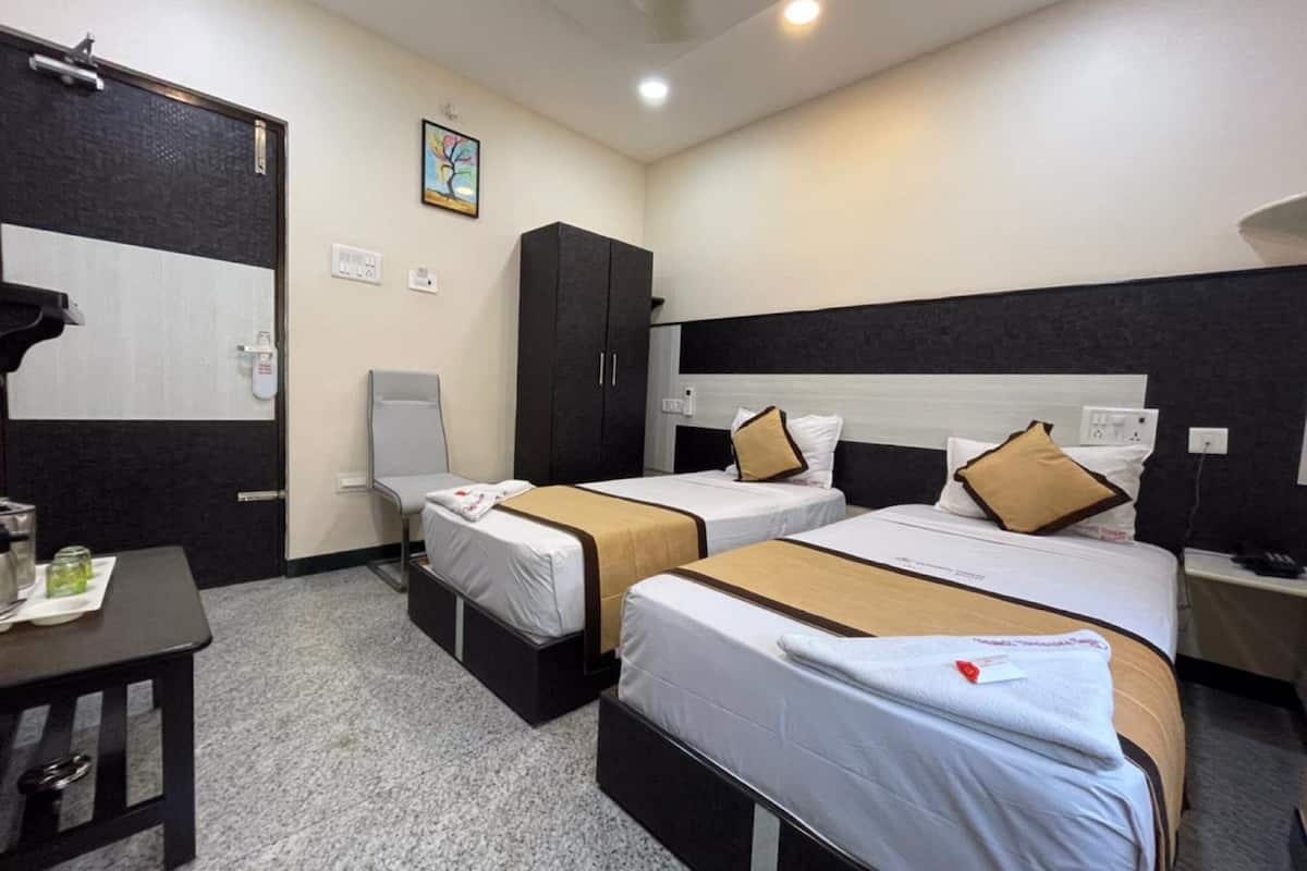 Quarto de hotel com duas camas, uma escrivaninha, um guarda-roupa e um quadro na parede.