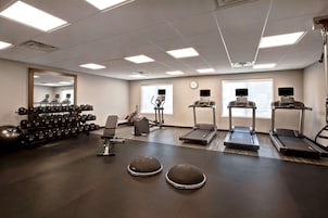 Academia com esteiras, halteres e bolas de exercício.