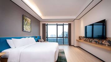 Quarto de hotel moderno com uma cama grande, televisão de tela plana, vista para a cidade e design minimalista.