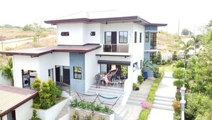 Uma casa moderna de dois andares com varanda, um pequeno jardim e piscina.