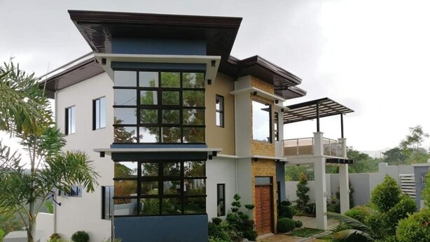 Uma casa moderna de dois andares, com amplas janelas, telhado plano e um jardim bem cuidado.