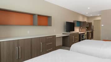 Quarto de hotel moderno com cozinha compacta, televisão de tela plana e uma cama.