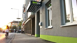 Um edifício com uma placa que diz 'best price hotels', uma placa 'Toscan' e uma parte inferior pintada de verde.