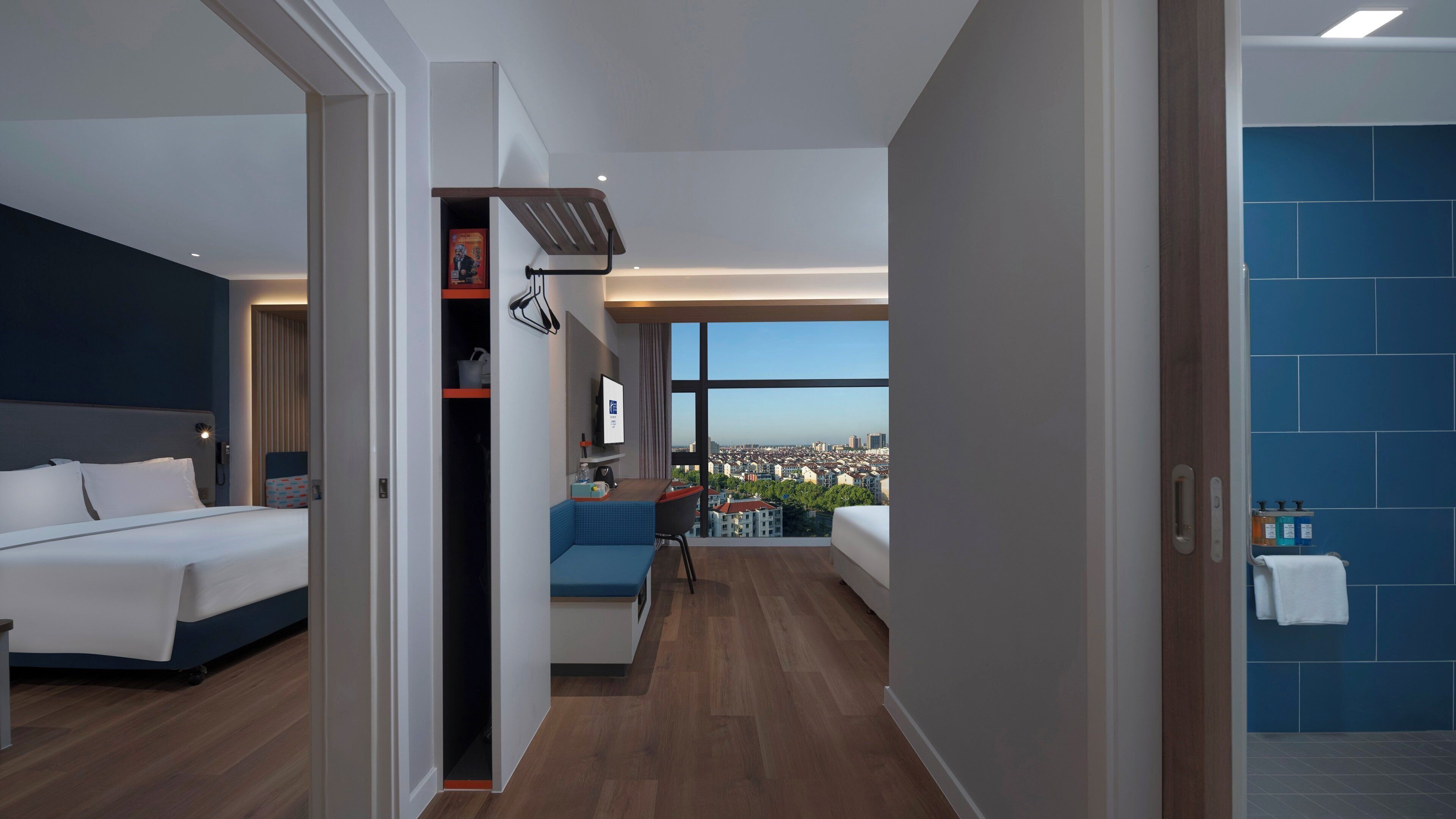Quarto de hotel moderno com uma cama grande, uma escrivaninha e vista para a cidade.