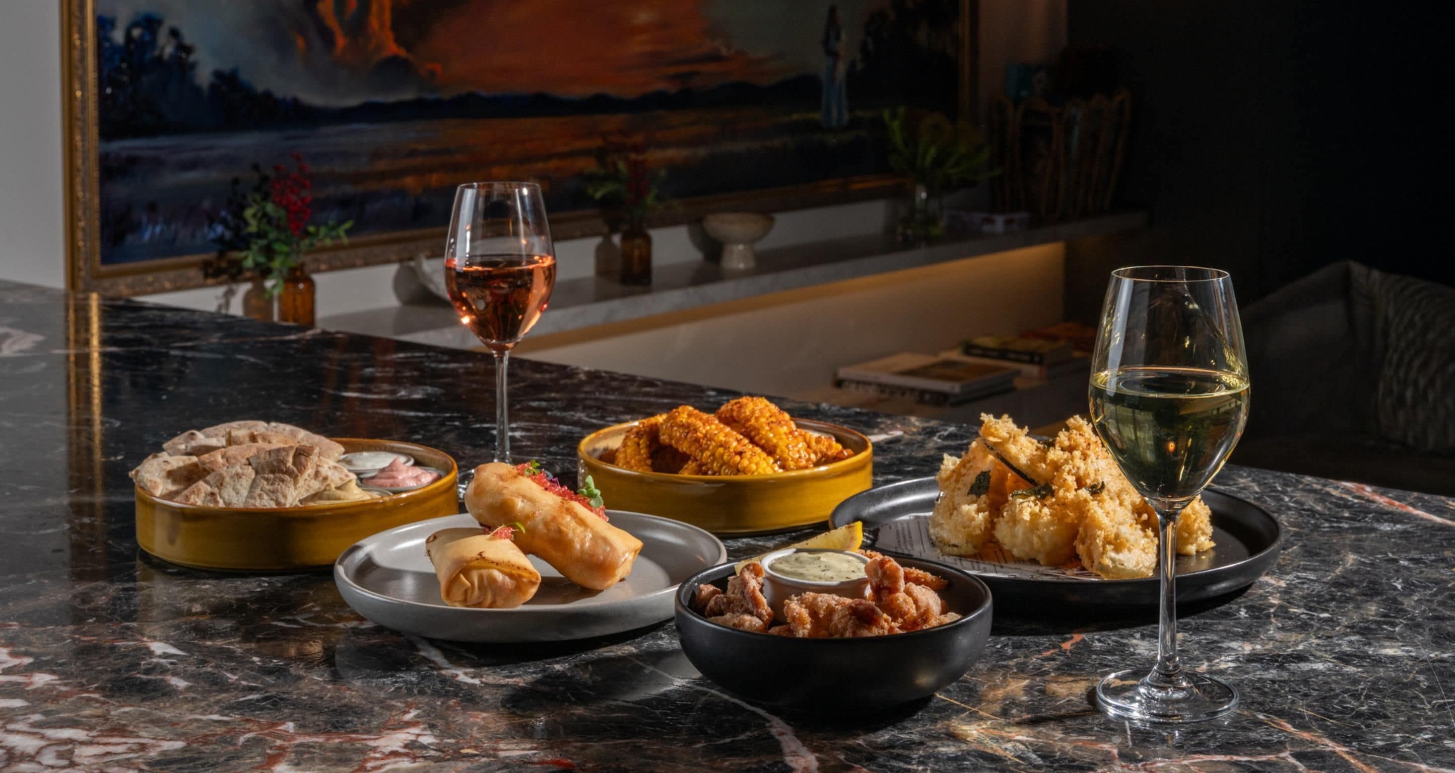 Uma mesa de jantar com diversos pratos e copos de vinho.