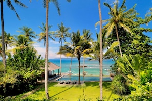 Um resort tropical com piscina, palmeiras e vista para o oceano.