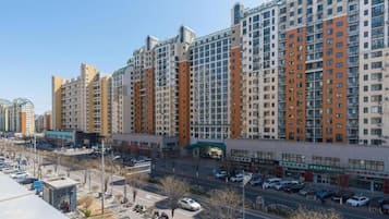 Um edifício residencial com vários andares, um pátio central, área de estacionamento e estabelecimentos comerciais no andar térreo.