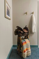 Um quarto com uma cadeira de madeira, um cobertor, uma toalha e um quadro na parede.