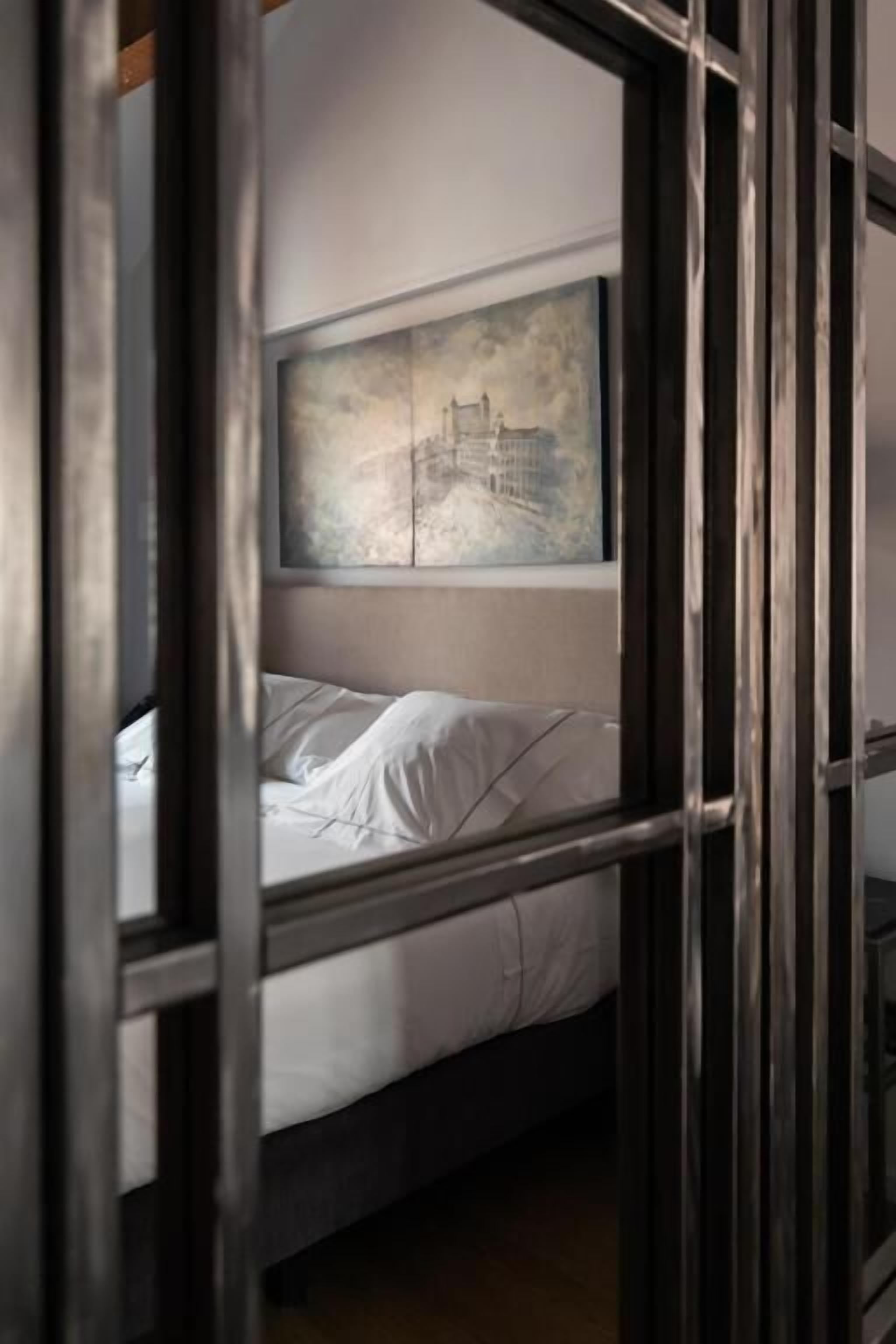 Quarto com cama, janela e um quadro na parede.
