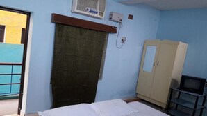 Quarto com cama, guarda-roupa, televisão em móvel e ar condicionado na parede.