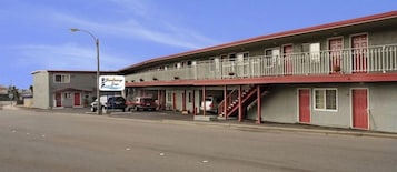 Um motel com fachada vermelha, varanda no segundo andar e uma placa.