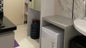 Casa de banho moderna com toucador de mármore, pequeno frigorífico e espelho grande.