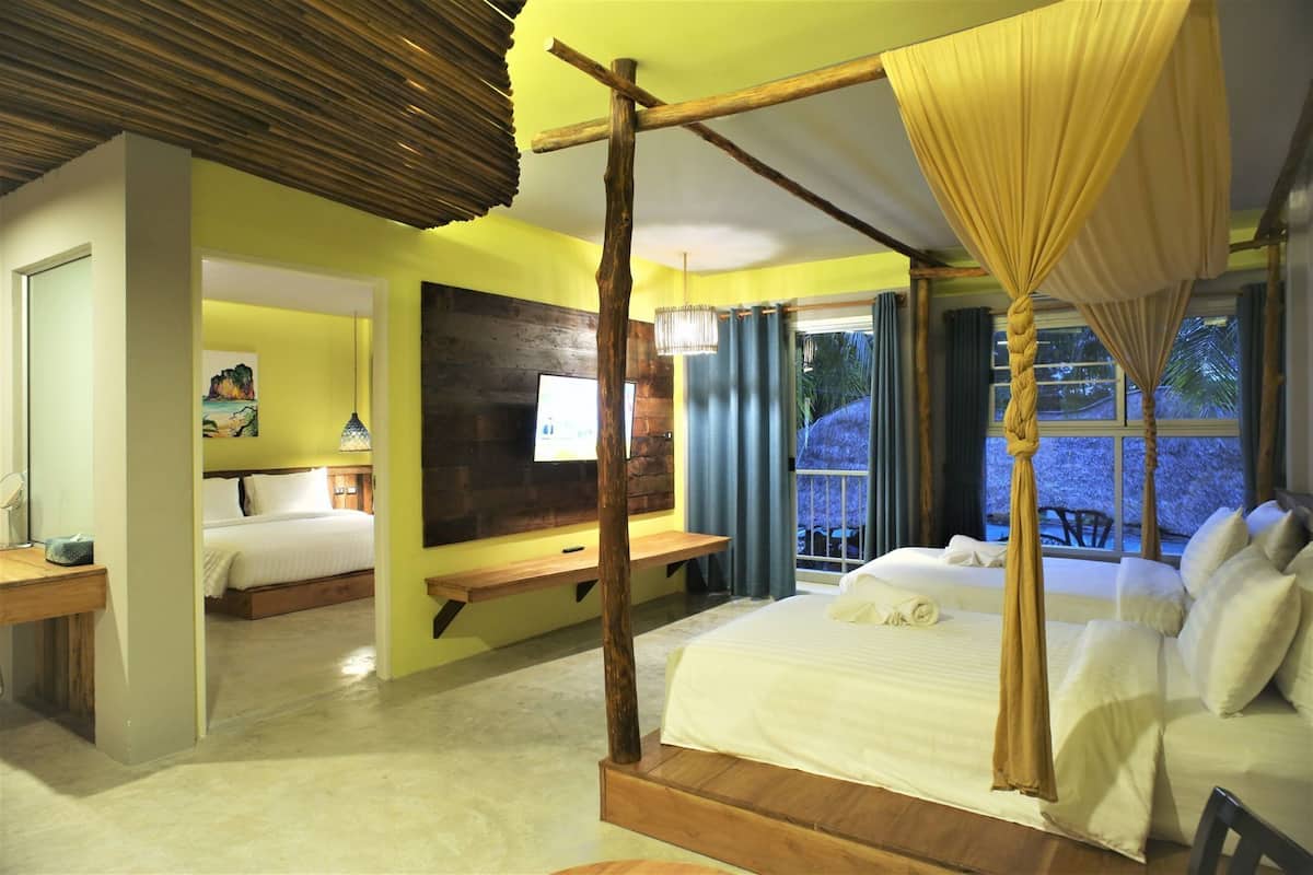 Quarto com uma cama de dossel, um banco de madeira, uma TV montada na parede e vista para o exterior.