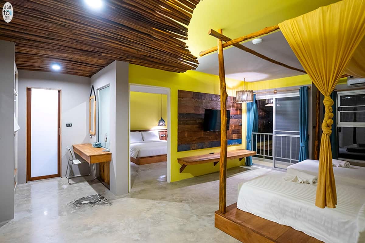Quarto de hotel moderno com teto de madeira, cama com dossel, escrivaninha e uma janela grande.