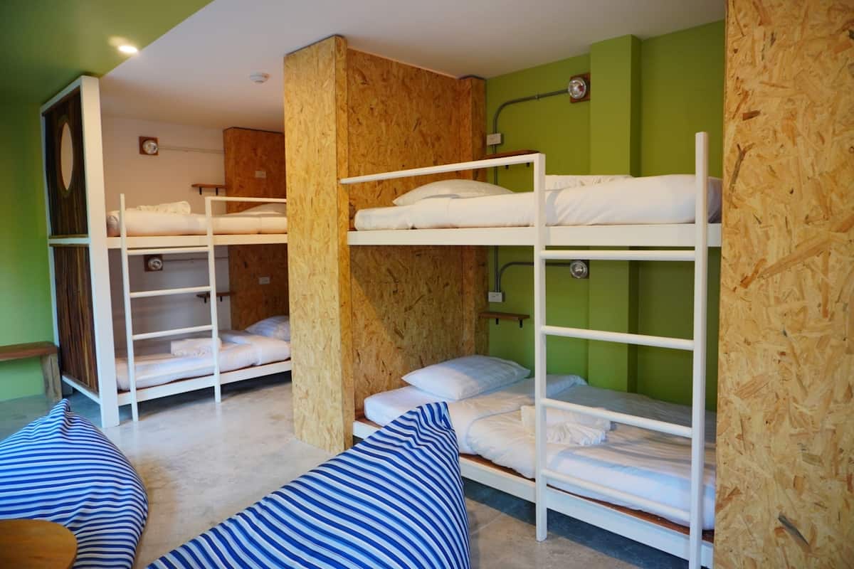 Quarto com beliches, paredes verdes e lambrisagem de madeira.