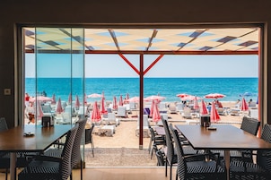 Restaurante à beira-mar com área externa e vista para o mar.