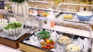Buffet com diversos alimentos em tigelas e recipientes, cercado por cubos de gelo.