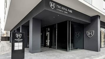 Entrada moderna de hotel com fachada escura e portas de vidro.