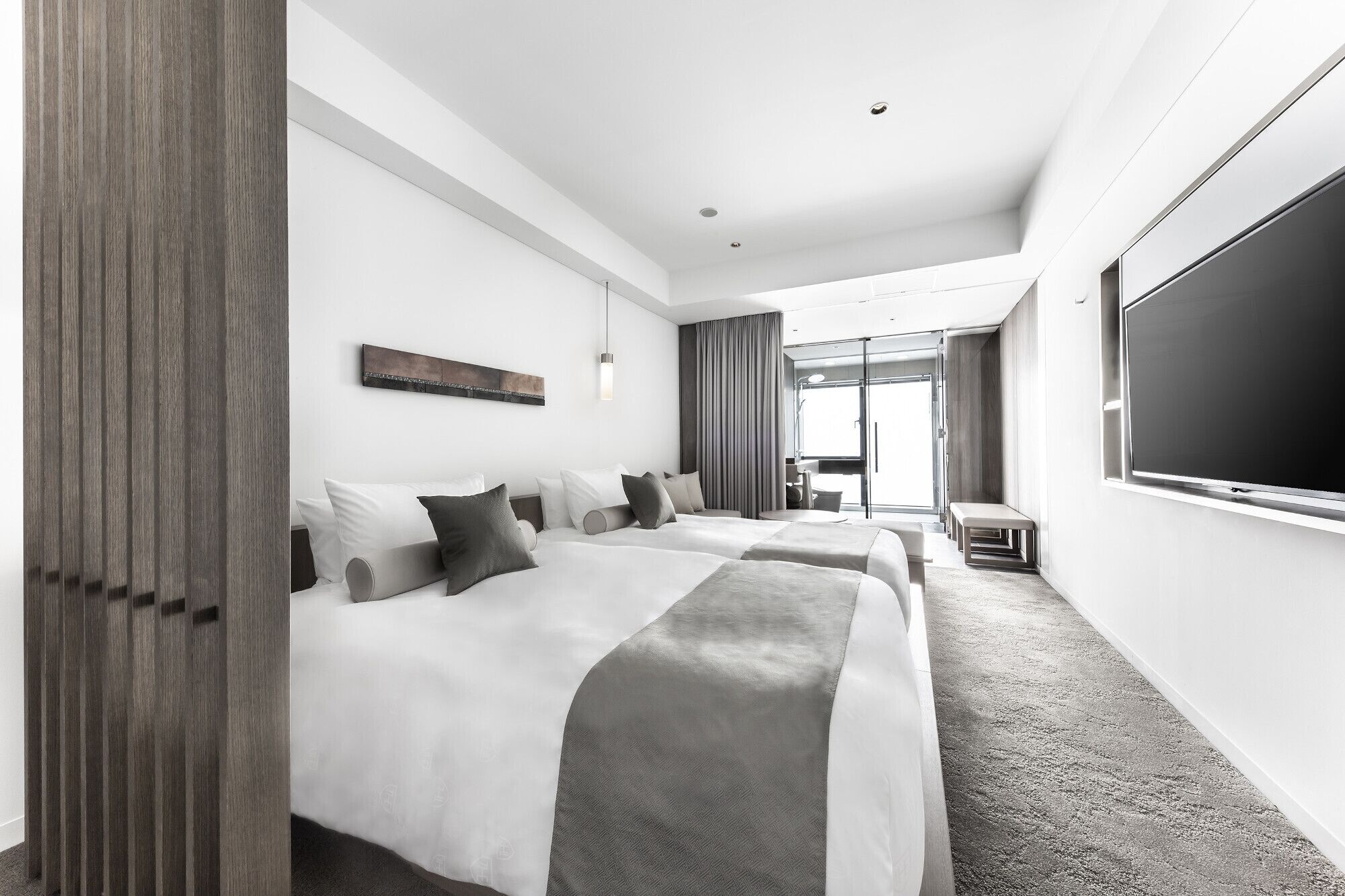 Quarto de hotel com duas camas, uma janela grande e vista para o exterior.