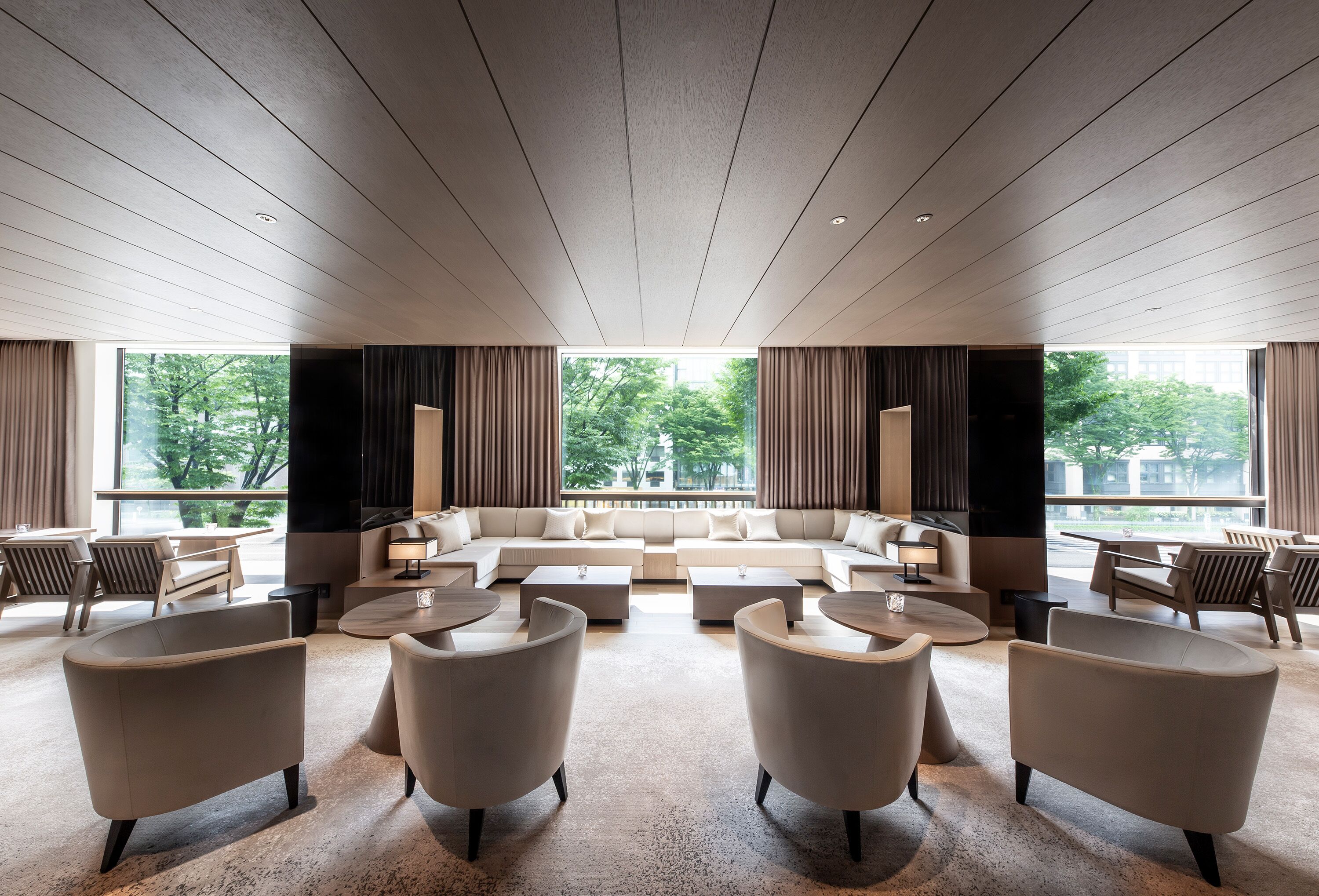 Um hall de hotel moderno com uma grande área de estar, uma mesa de centro e vista para o exterior.