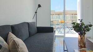 Uma sala de estar moderna com um sofá cinzento, um abajur e vista para a varanda.