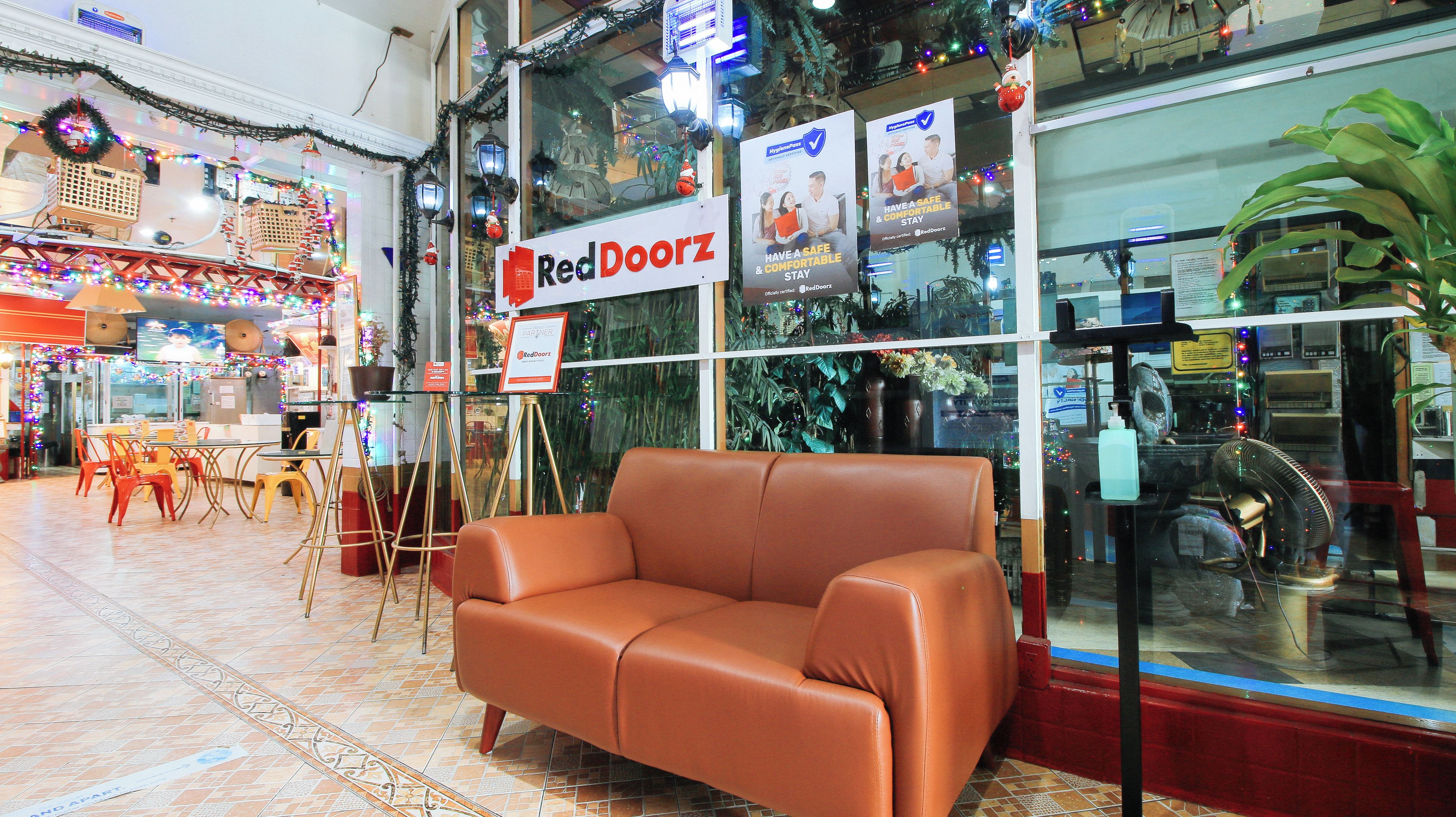 Uma loja RedDoorz com um sofá de couro marrom em frente.