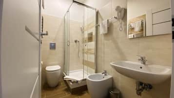 Uma casa de banho moderna com cabine de duche em vidro, bidé, lavatório e sanita.