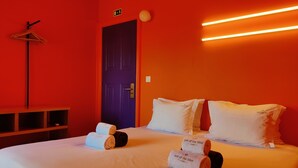 Quarto de hotel com cama, almofadas e uma toalha com texto.