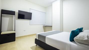 Quarto de hotel moderno com uma cama, guarda-roupa, televisão de ecrã plano e um quadro de avisos na parede.