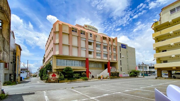 Hotel com design moderno, destacando um pilar vermelho e uma placa de identificação.
