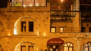 Um edifício de pedra com janelas em arco e uma placa com a inscrição 'Olivia Cave Hotel'.