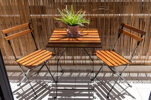 Uma mesa de madeira com um vaso de planta no centro, rodeada por duas cadeiras de madeira.