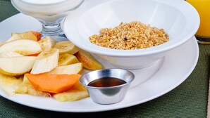 Mesa posta para o café da manhã com panquecas, café, frutas e cereais.