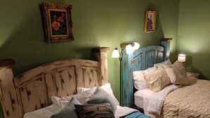 Quarto com duas camas, cada uma com cabeceira, e uma parede verde. Há duas imagens emolduradas na parede.