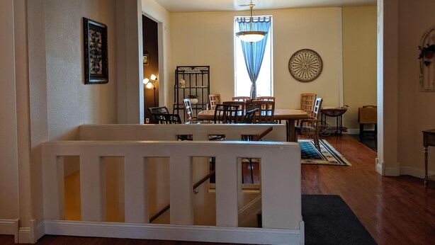 Uma área de refeições com mesa e cadeiras de madeira, um candelabro e um objeto decorativo na parede.