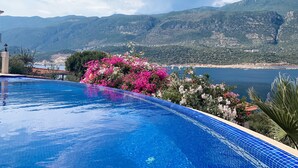 Piscina com vista para montanhas e um corpo d'água.