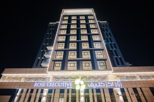 Edifício de hotel com letreiros iluminados que dizem "ROSE EXECUTIVE Hotel".