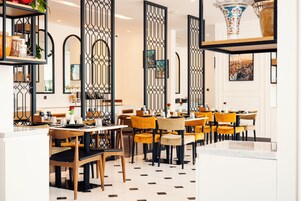 Um restaurante moderno com cadeiras amarelas, decoração preta e branca e chão de azulejos.