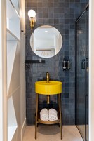 Casa de banho com lavatório amarelo, espelho e toalheiro.